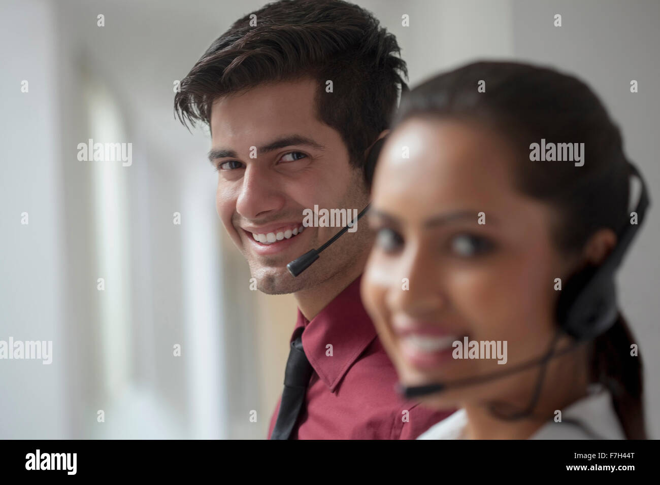 India, Male telemarketer sitting behind female telemarketer smiling ...