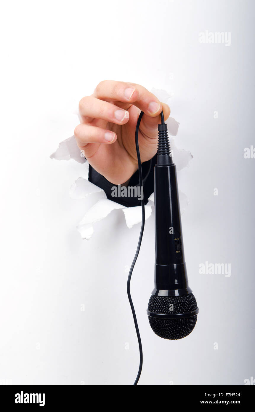 Hand holding microphone through hole in paper Stock Photo - Alamy