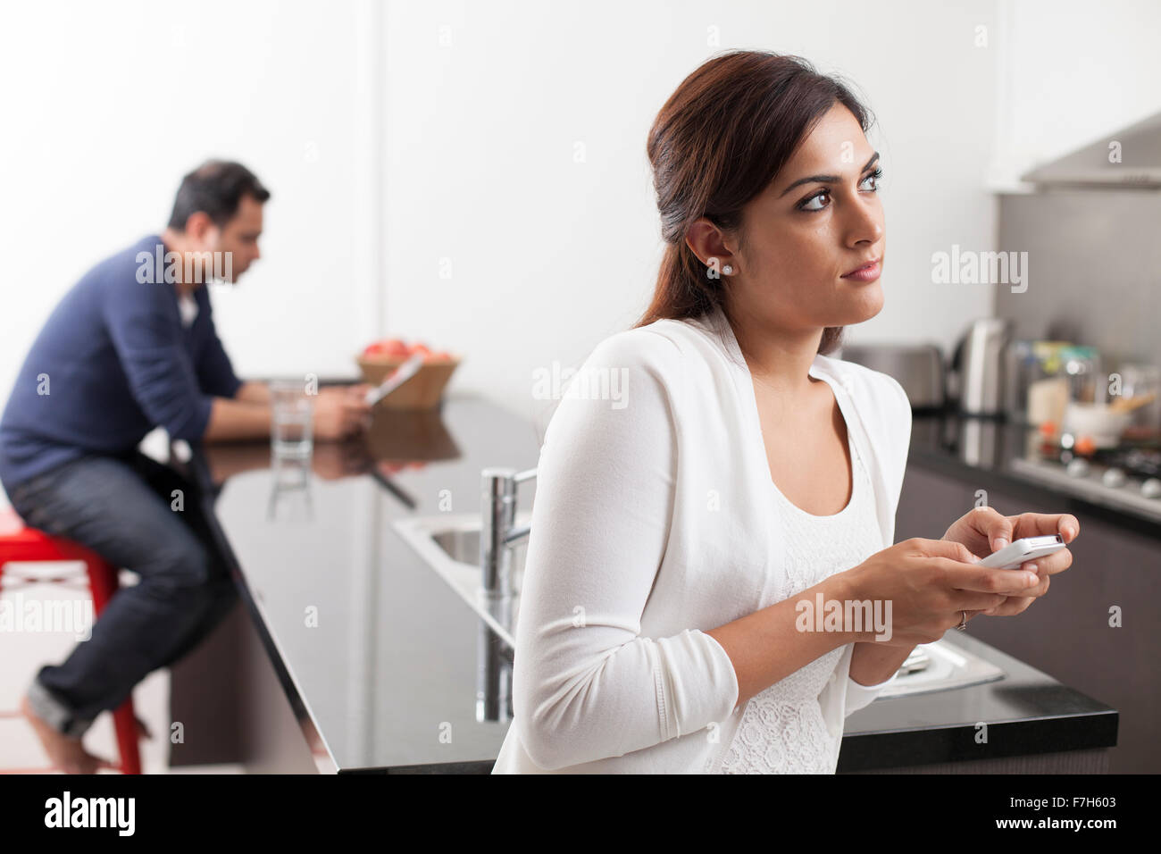 Singapore, Young woman texting in kitchen Stock Photo - Alamy