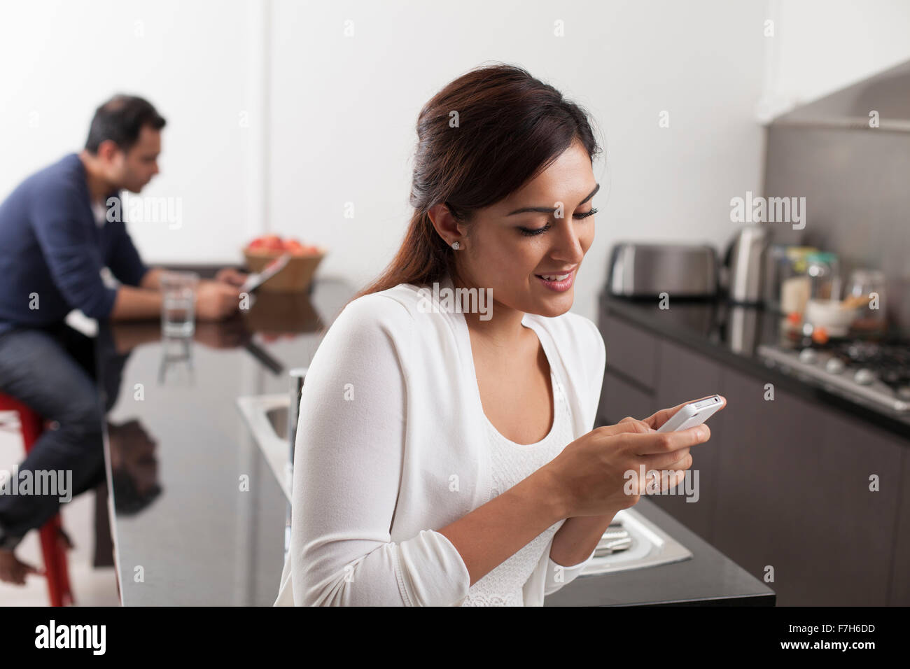 Singapore, Young woman texting in kitchen Stock Photo - Alamy