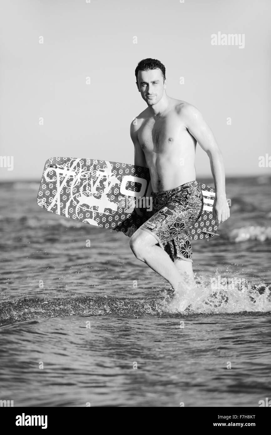 Portrait of a strong young surf man at beach on sunset in a ...