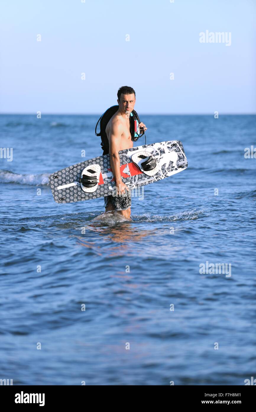 Portrait of a strong young surf man at beach on sunset in a ...