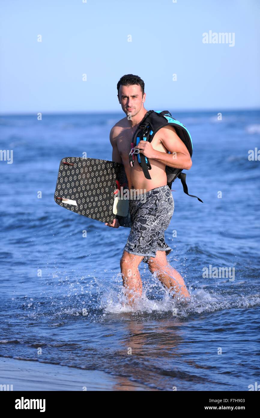 Portrait of a strong young surf man at beach on sunset in a ...