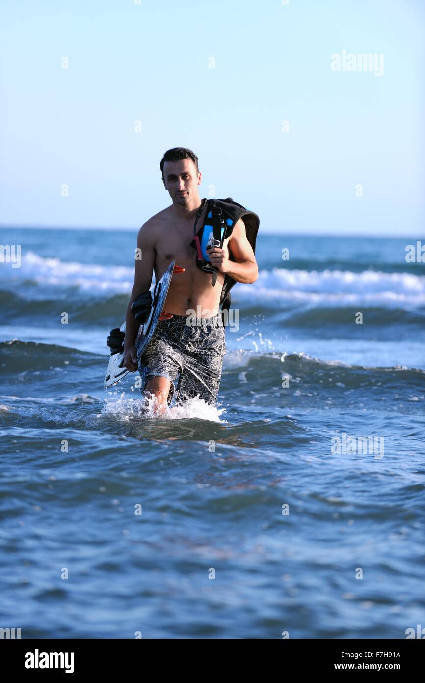 Portrait of a strong young surf man at beach on sunset in a ...