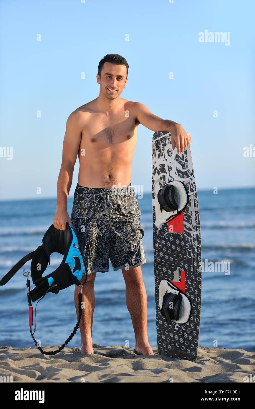 Portrait of a strong young surf man at beach on sunset in a ...