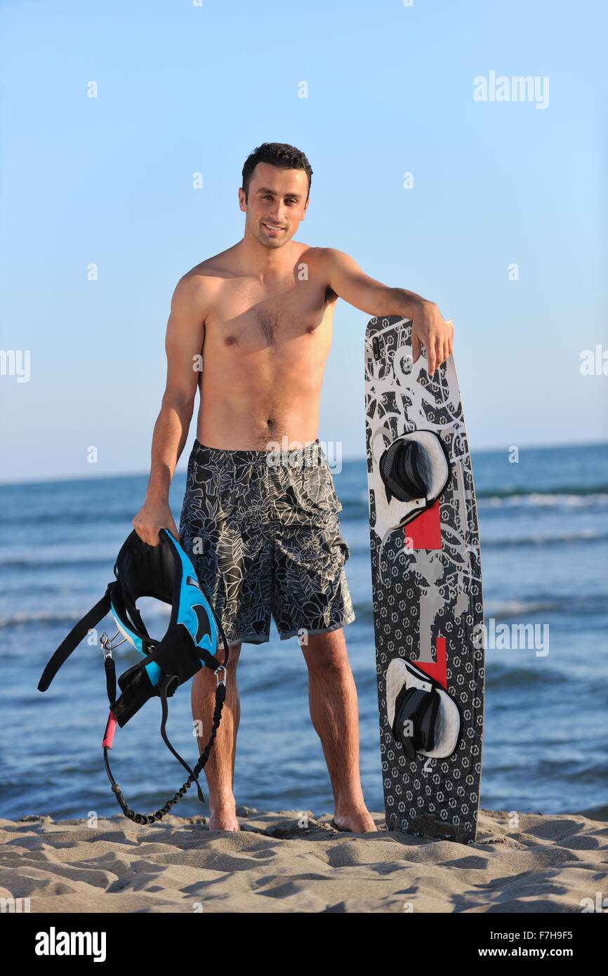 Portrait of a strong young surf man at beach on sunset in a ...
