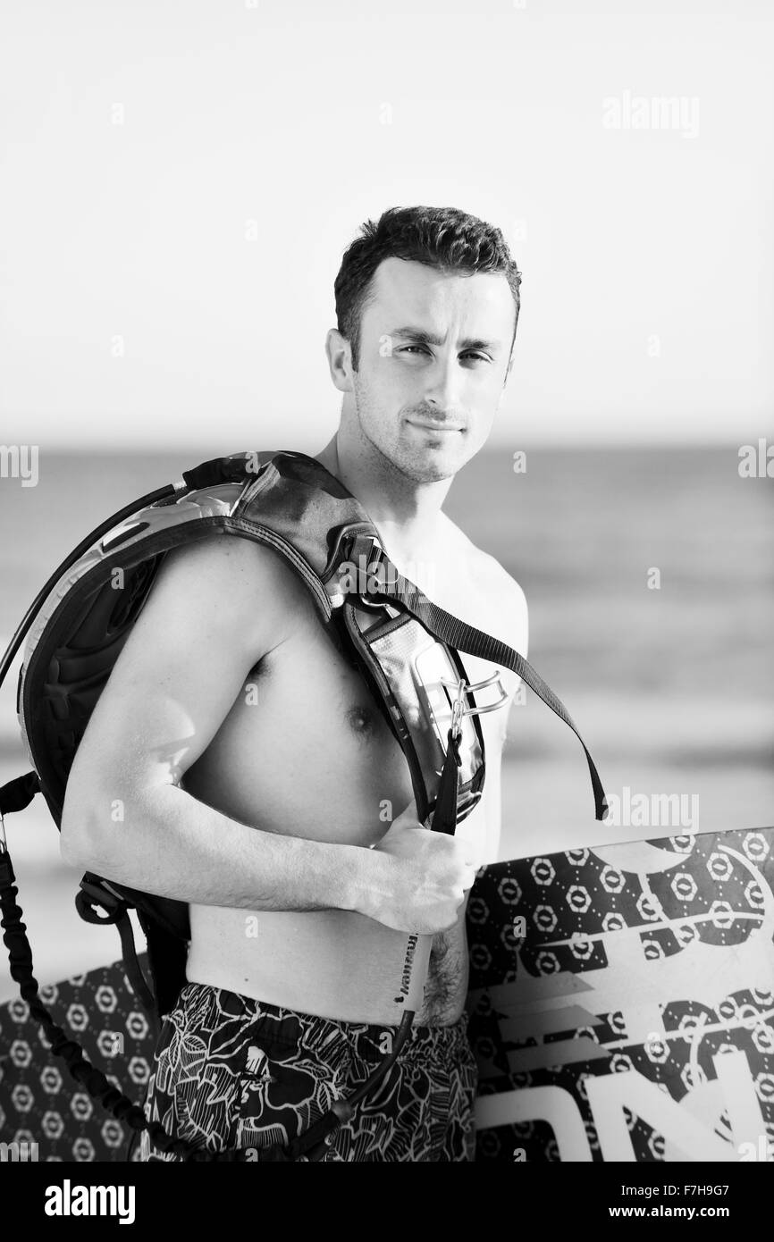 Portrait of a strong young surf man at beach on sunset in a ...