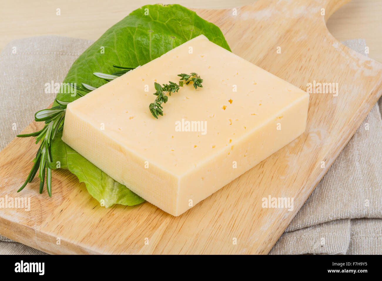 Yellow cheese brick with rosemary and thyme Stock Photo - Alamy