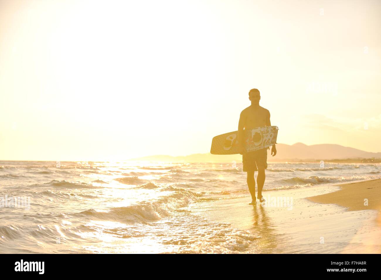 Portrait of a strong young surf man at beach on sunset in a ...