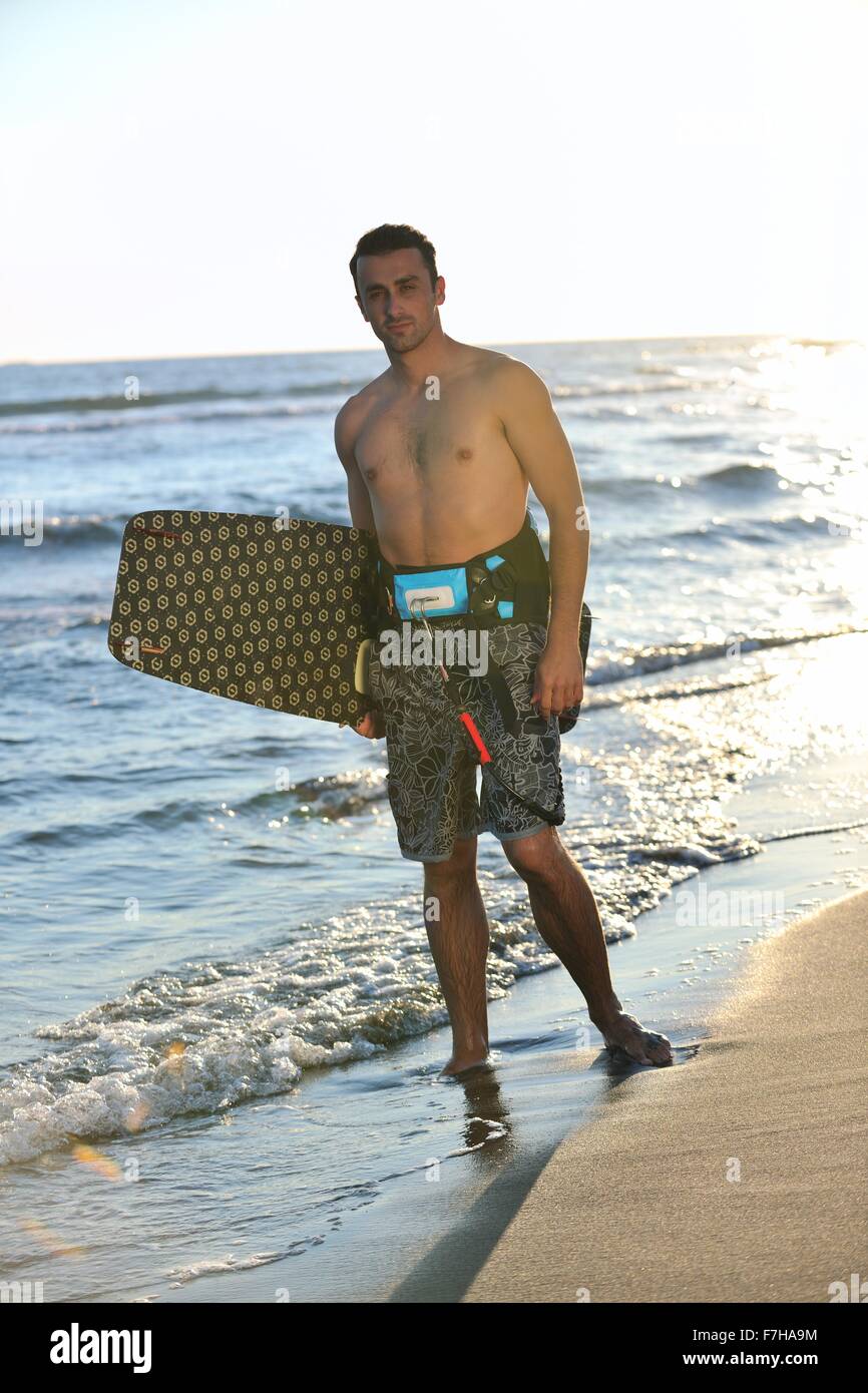 Portrait of a strong young surf man at beach on sunset in a ...