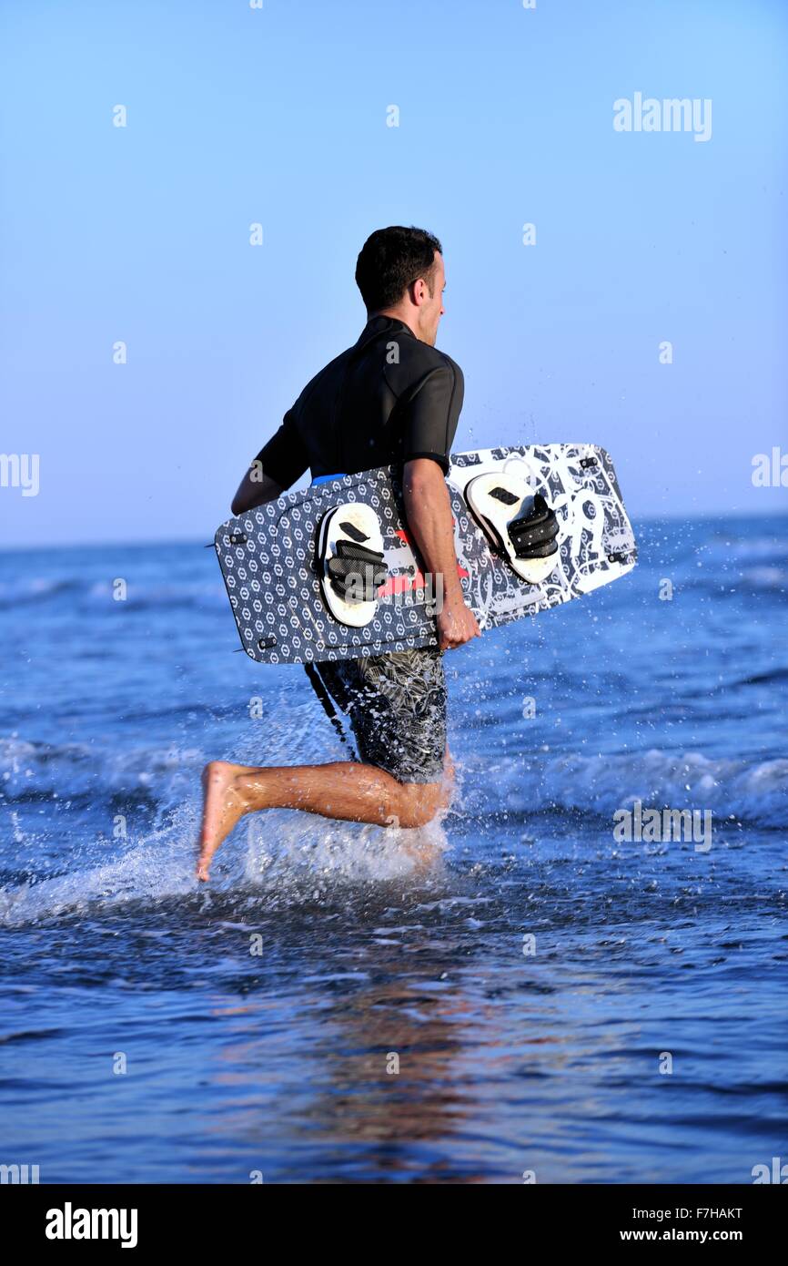 Portrait of a strong young surf man at beach on sunset in a ...