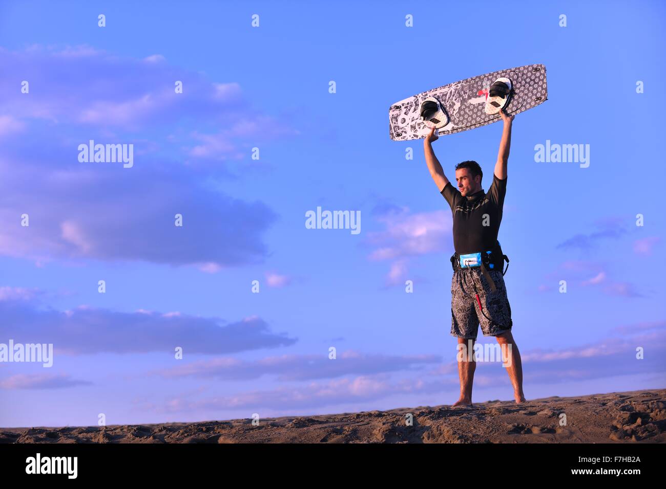 Portrait of a strong young surf man at beach on sunset in a ...