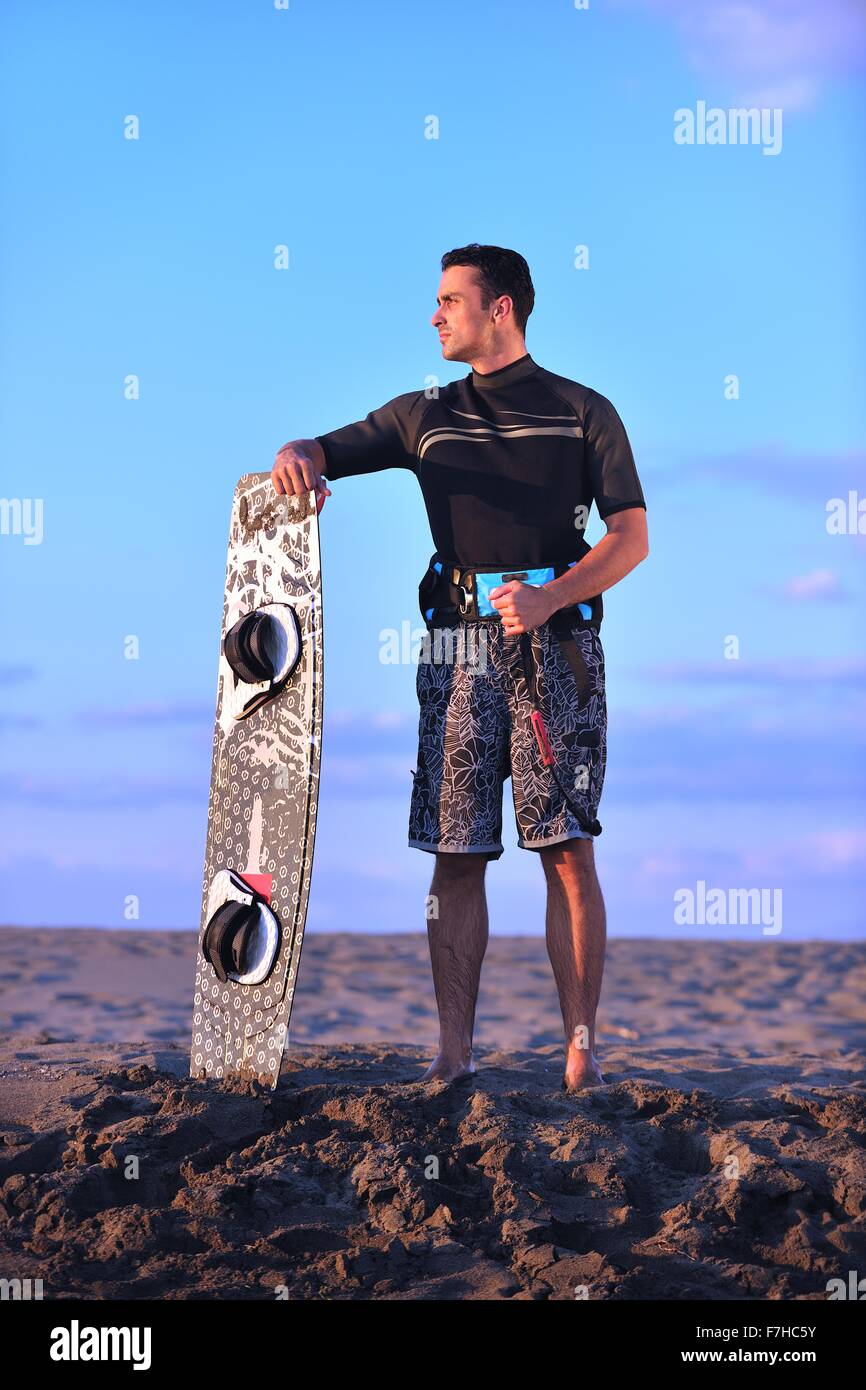Portrait of a strong young surf man at beach on sunset in a ...