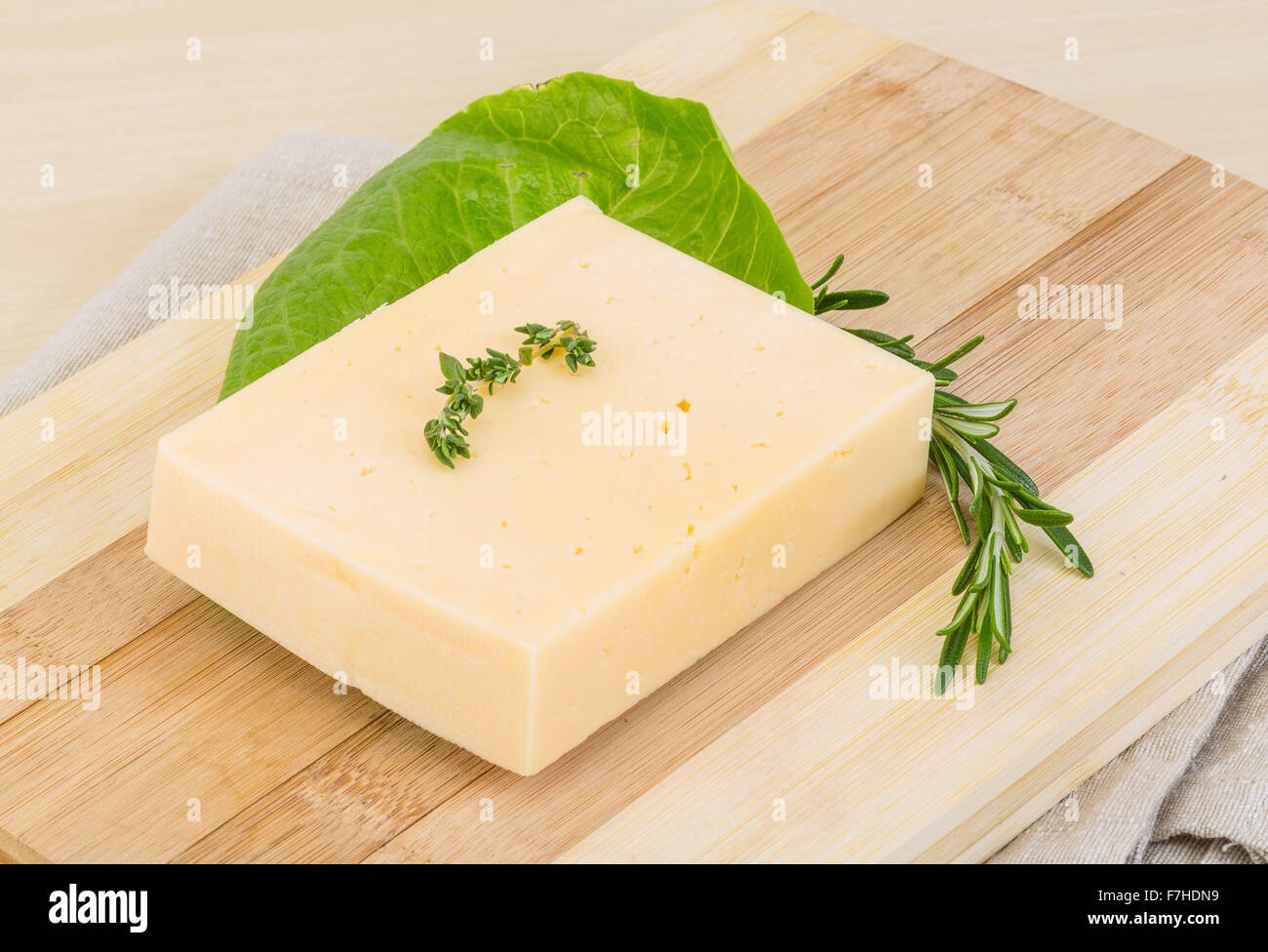 Yellow cheese brick with rosemary and thyme Stock Photo - Alamy
