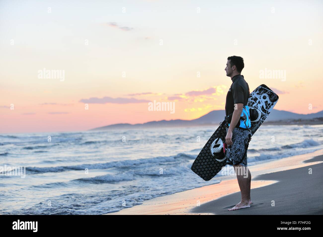Portrait of a strong young surf man at beach on sunset in a ...