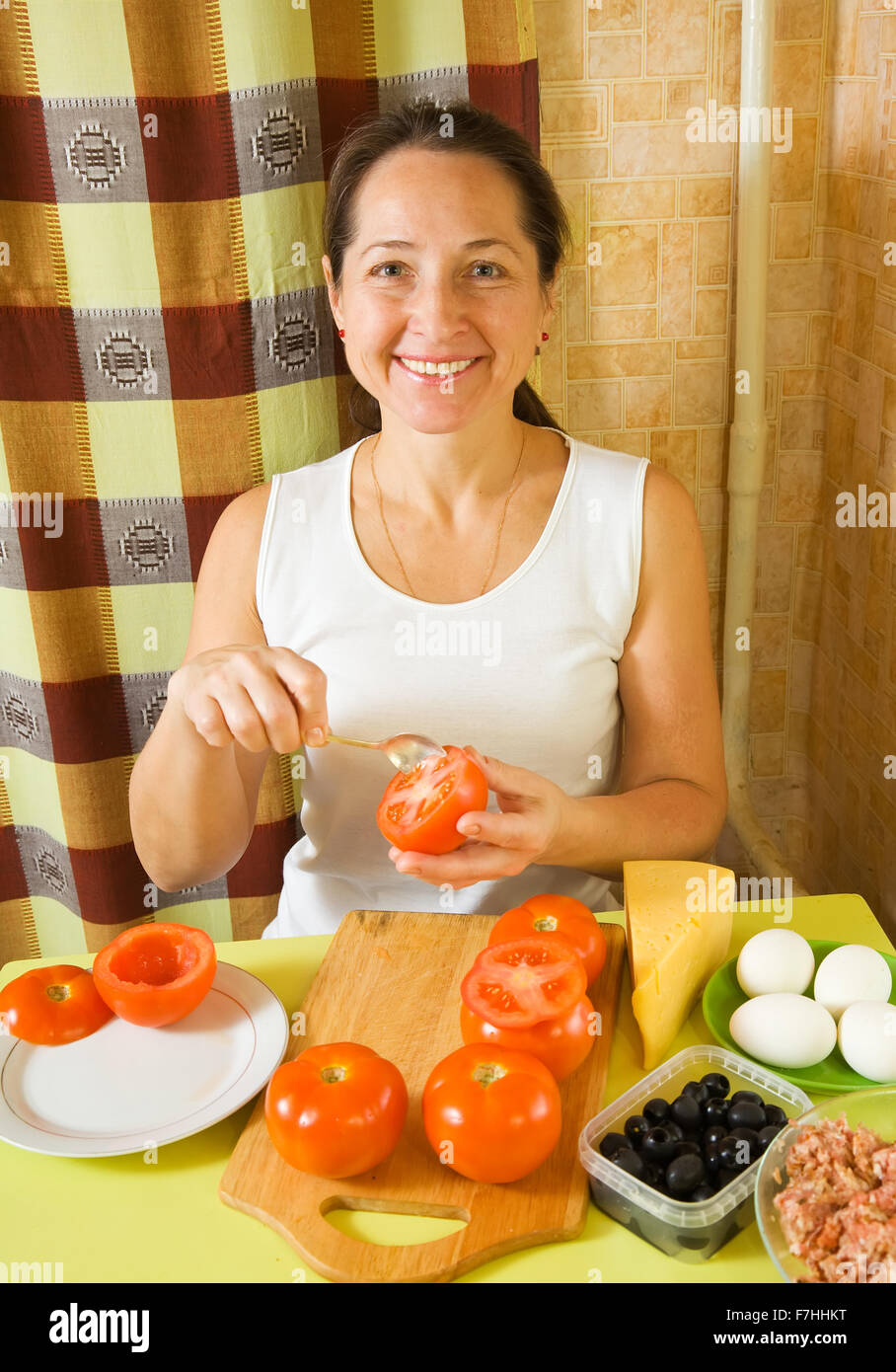 Woman cooking farci tomato in her kitchen. See in series stages of ...