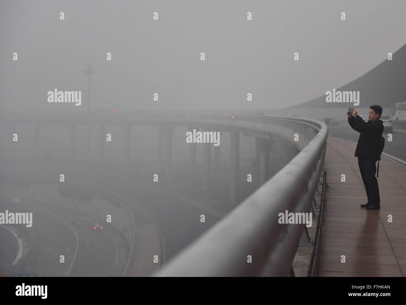 Beijing, China. 1st Dec, 2015. A man takes photos of the fog at Capital ...