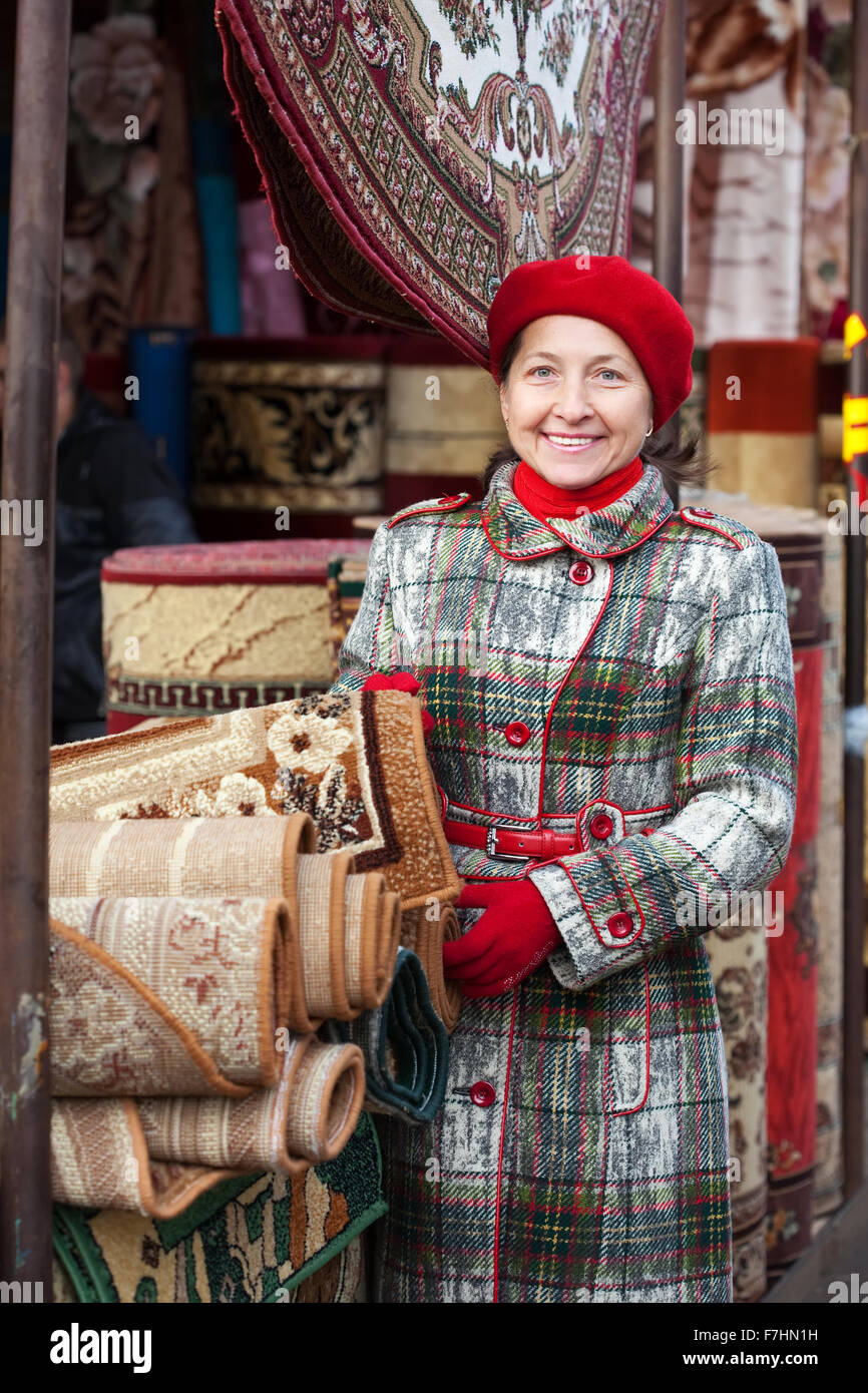 Mature woman chooses rug at market Stock Photo - Alamy