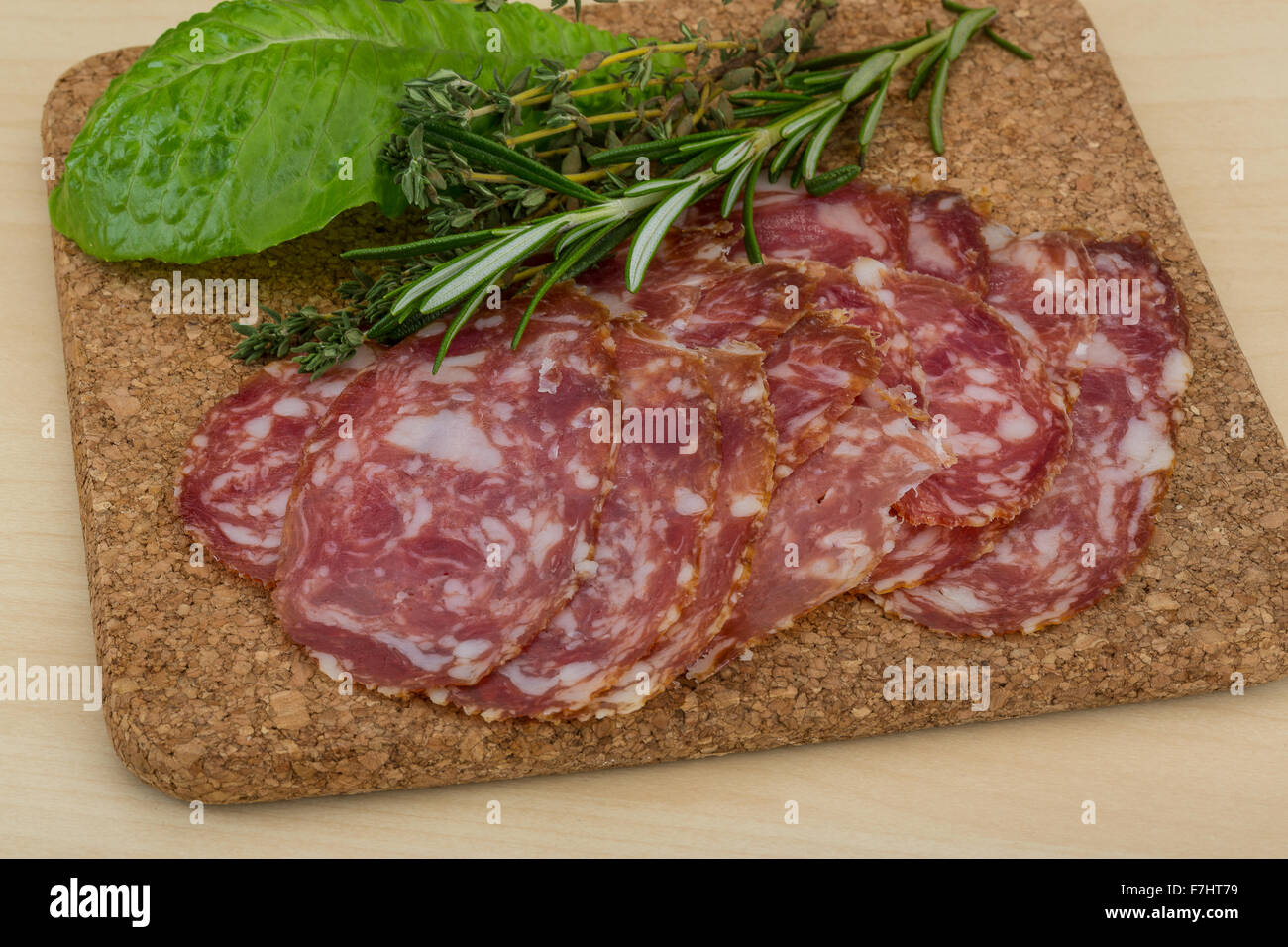 Sliced Salami with herbs on the wooden bckground Stock Photo - Alamy