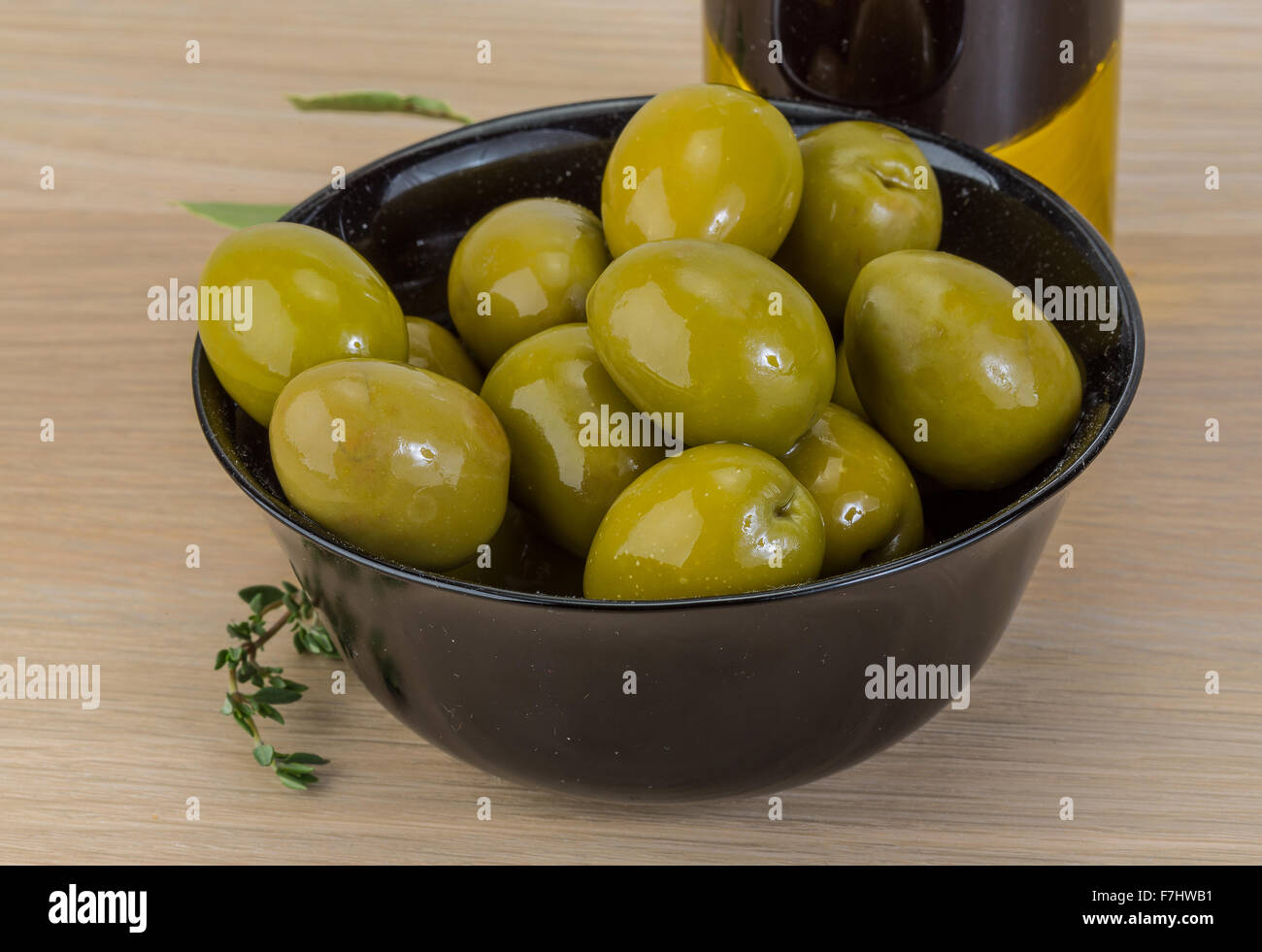 Green olives in the bowl with thyme branch Stock Photo - Alamy