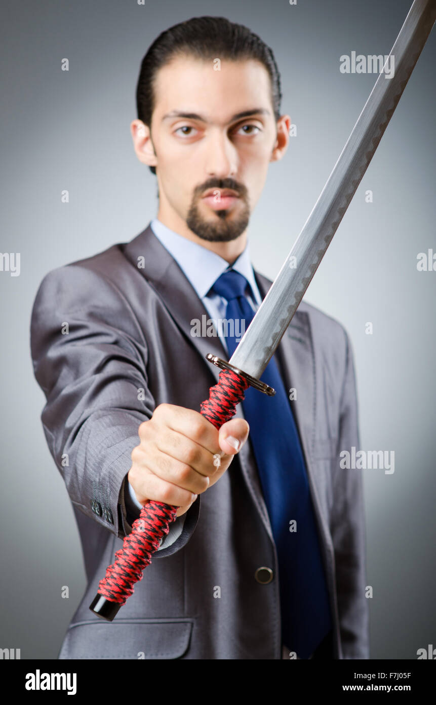 Angry businessman with sword in dark room Stock Photo - Alamy