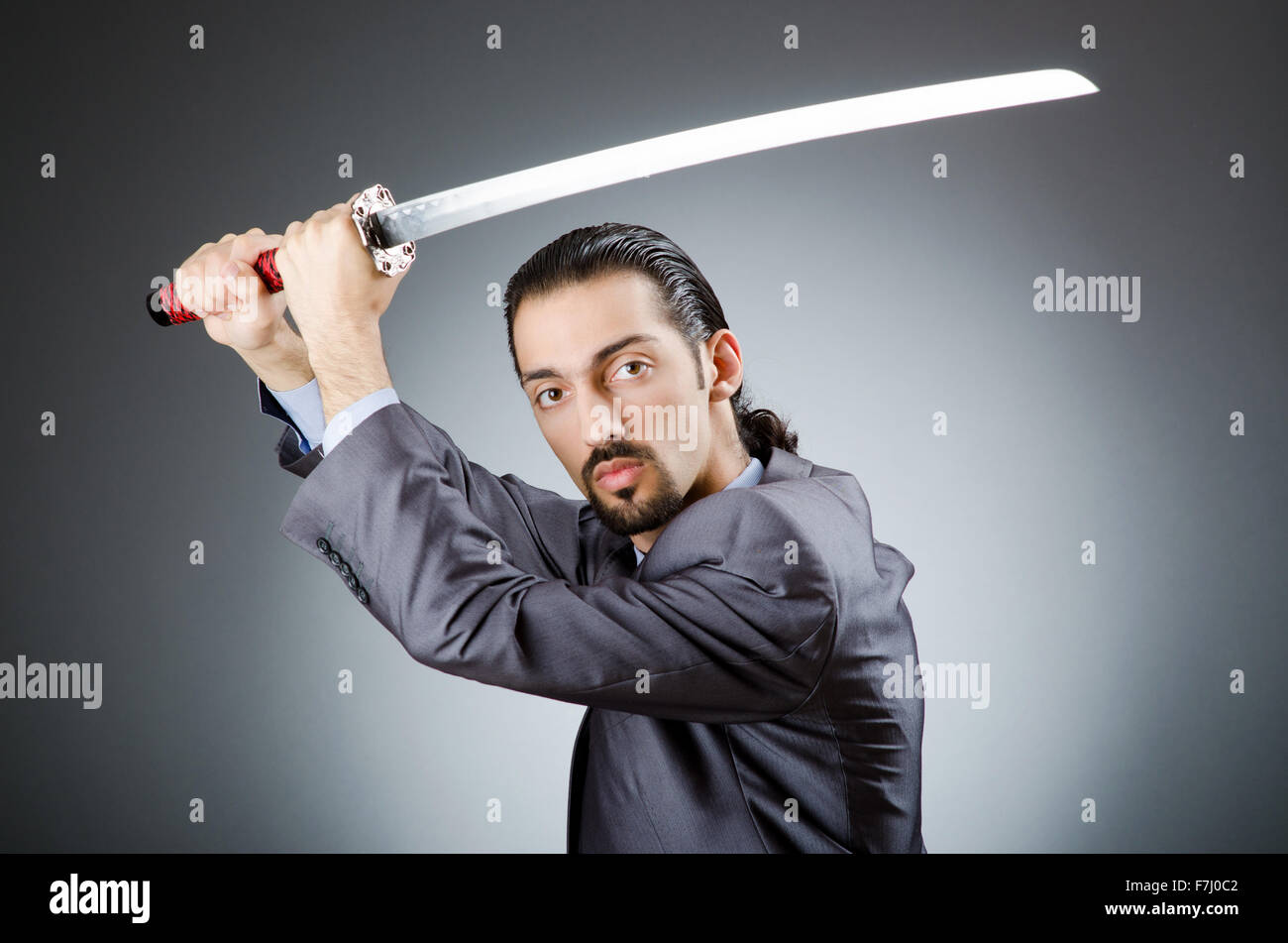 Angry businessman with sword in dark room Stock Photo - Alamy