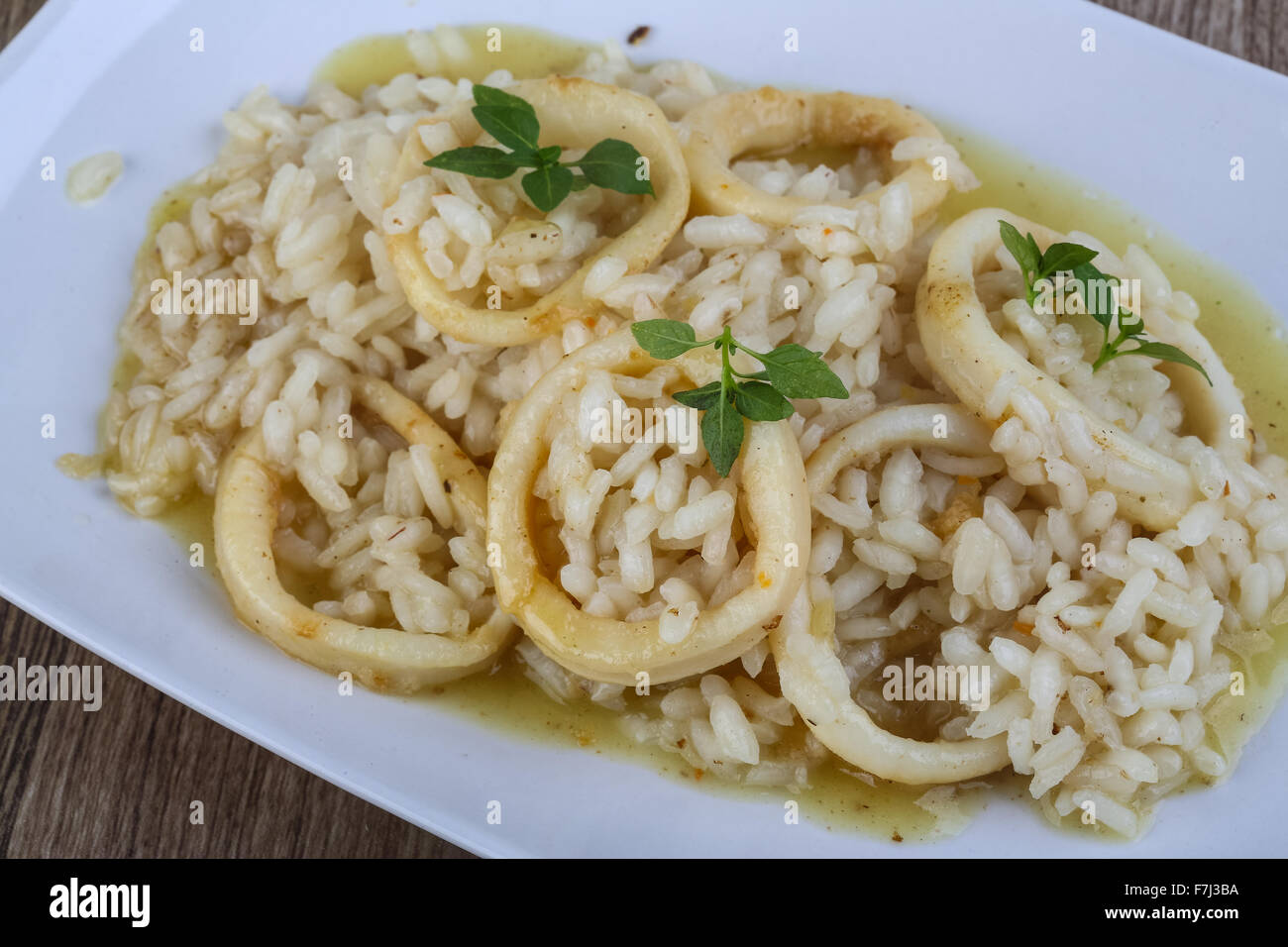 Italian famous cuisine - Squid risotto served basil leaves Stock Photo ...