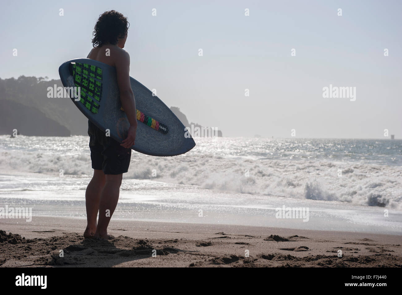 Surfer standing at water's edge, looking at sea Stock Photo - Alamy