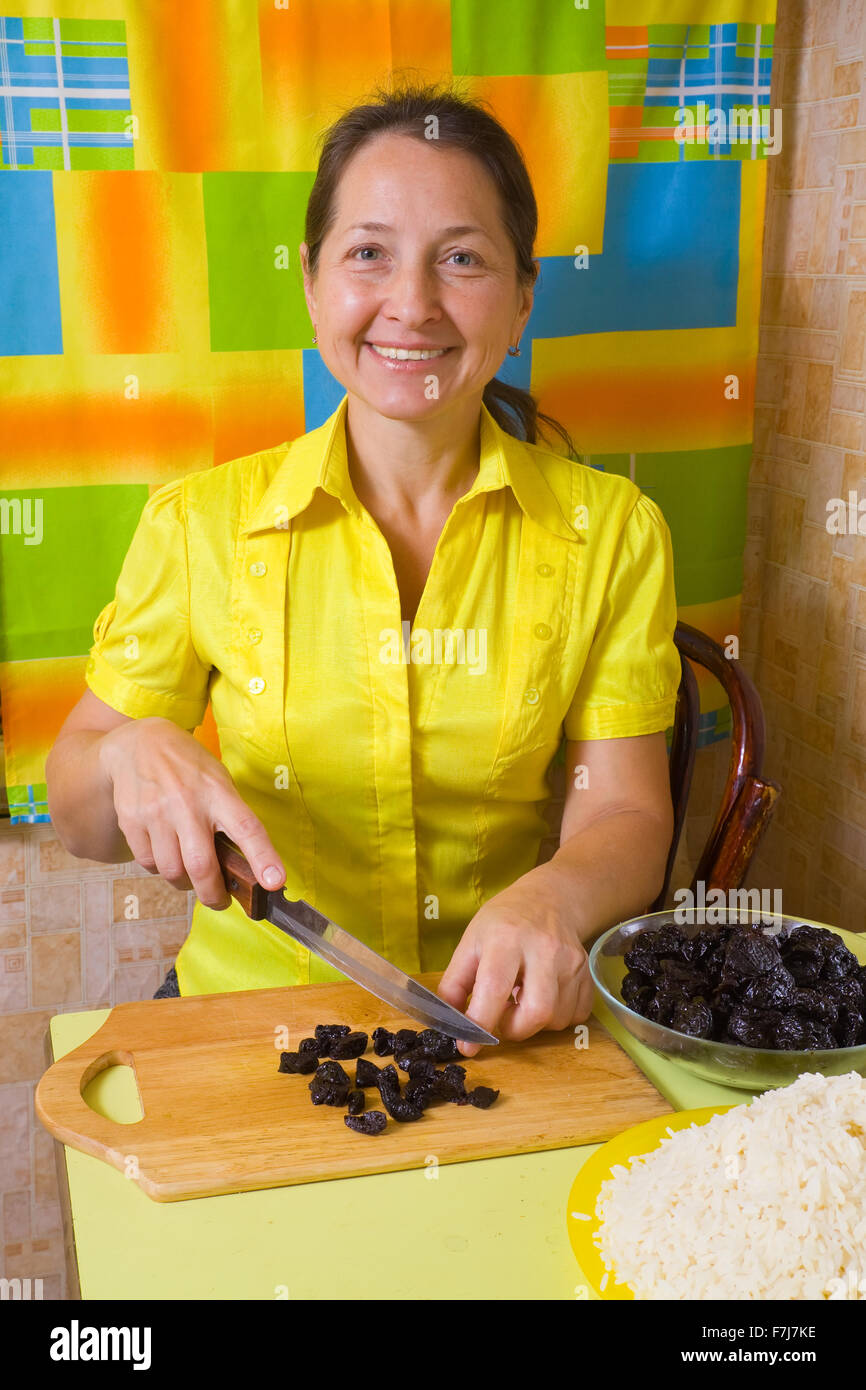 Mature woman slicing prune on cutting board in her kitchen Stock Photo ...