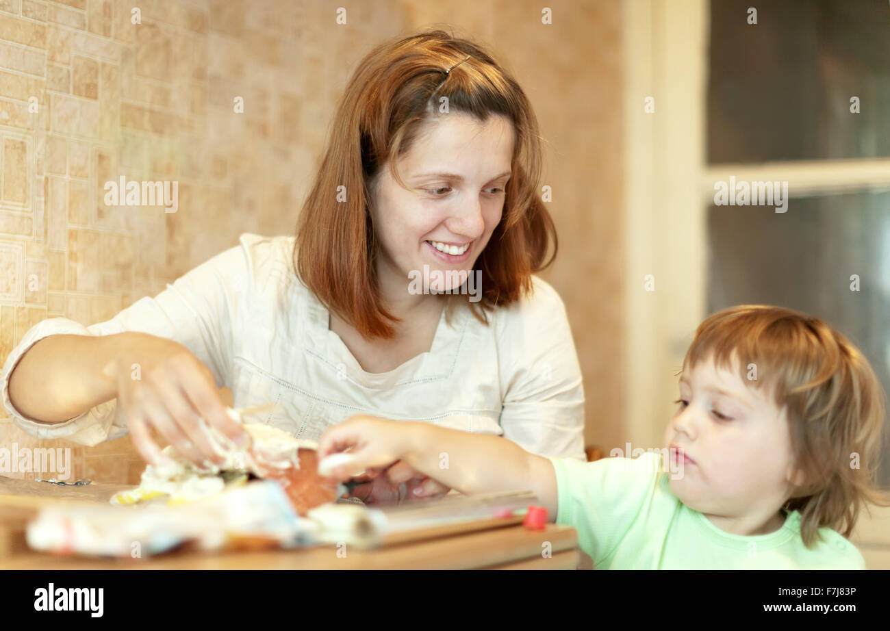 Happy mother with girl foiling fish at kitchen. Focus on woman Stock ...