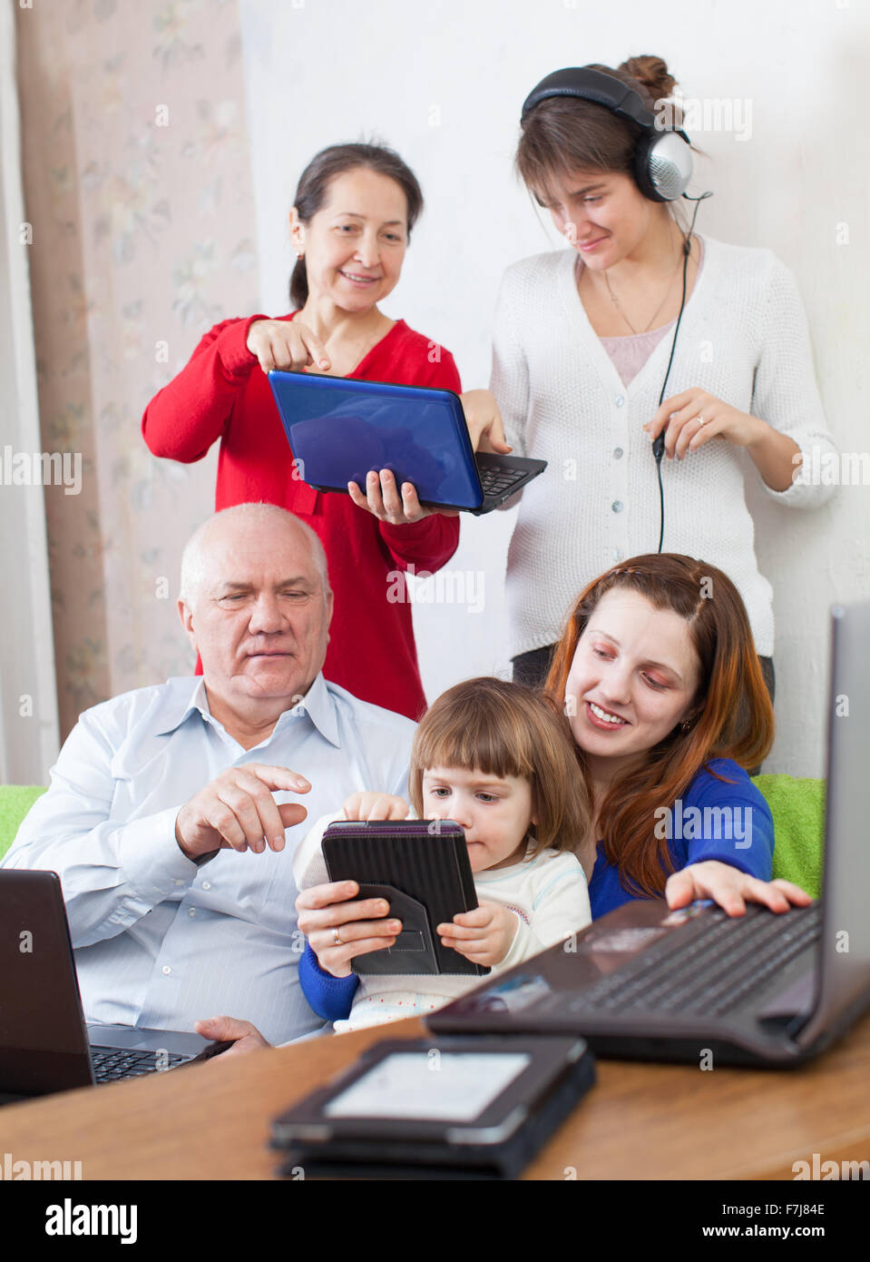 Happy multigeneration family uses few various electronic devices in ...