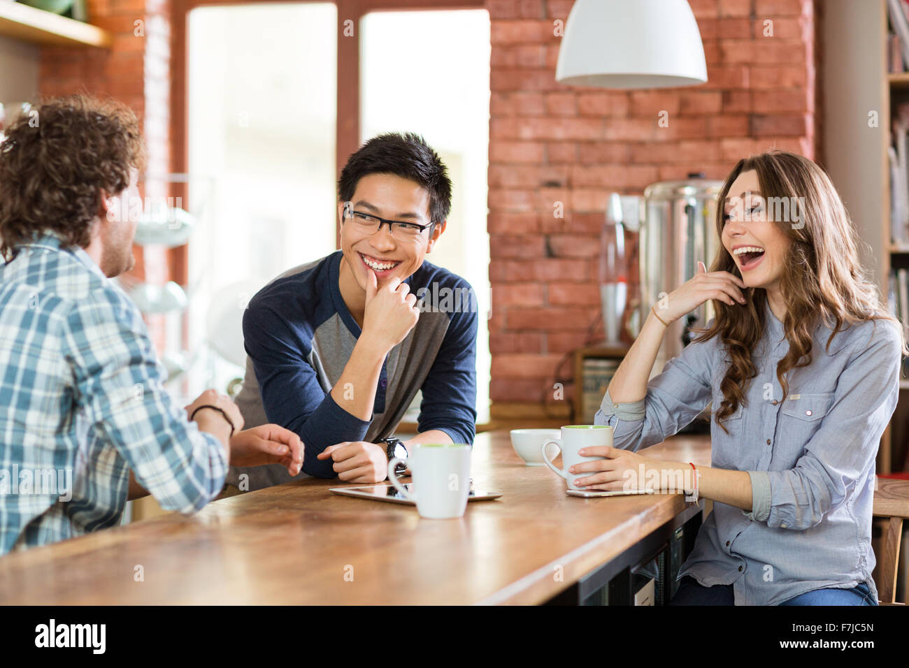 Happy positive friends drinking tea and laughing in cafe Stock Photo ...