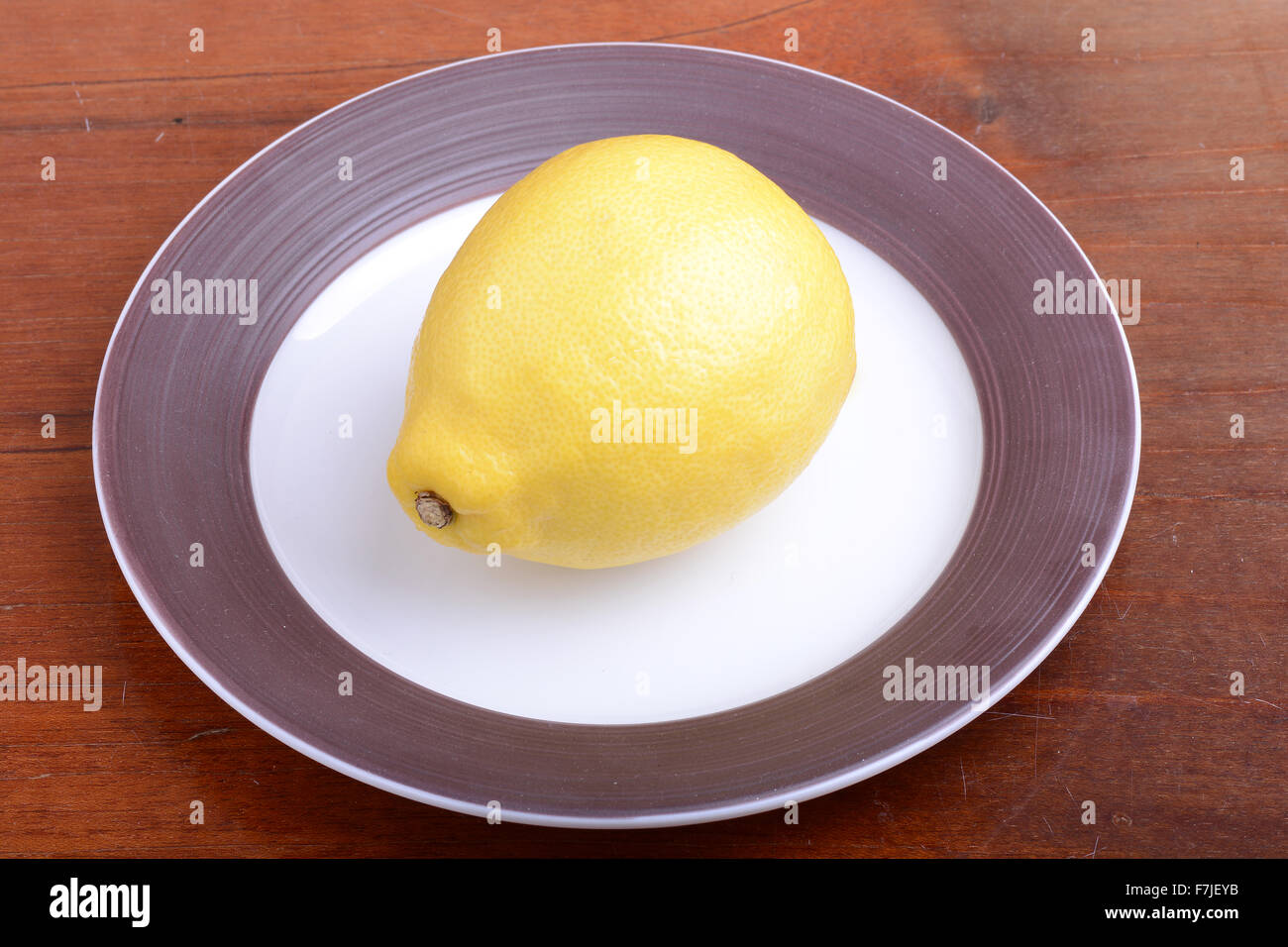 Whole lemon on a grey plate on wooden background Stock Photo - Alamy