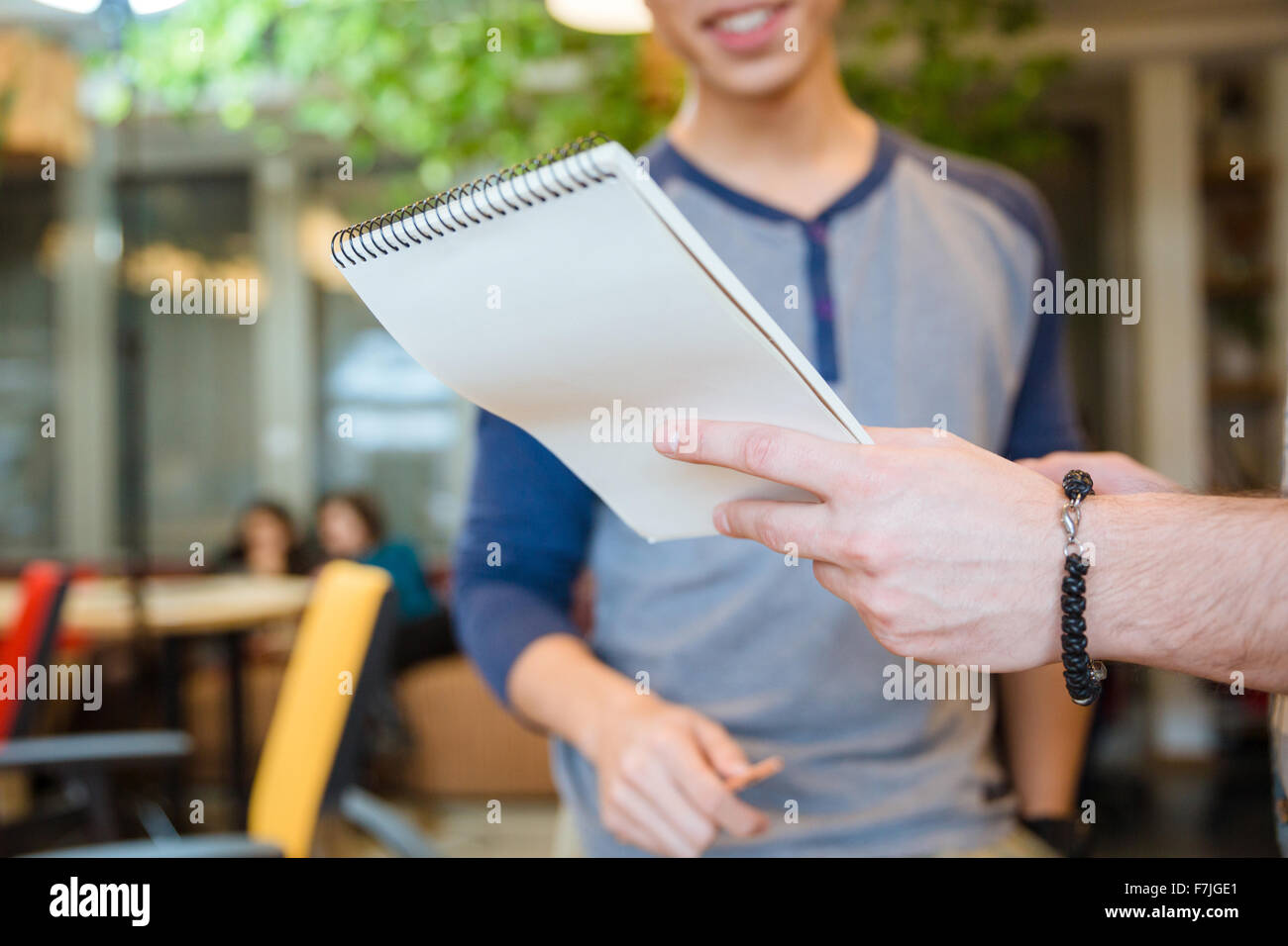 Closeup of male hand showing his notes to young cheerful guy Stock ...