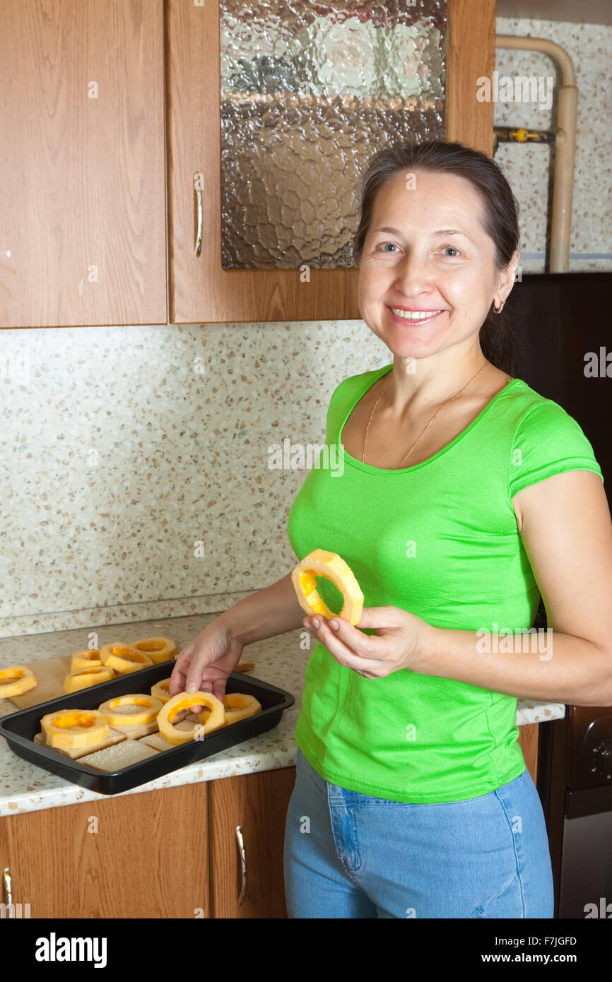 Woman puts vegetable marrow ring into roasting tray. See in series ...