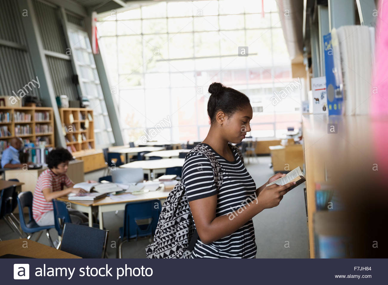 High school student reading book in library Stock Photo - Alamy
