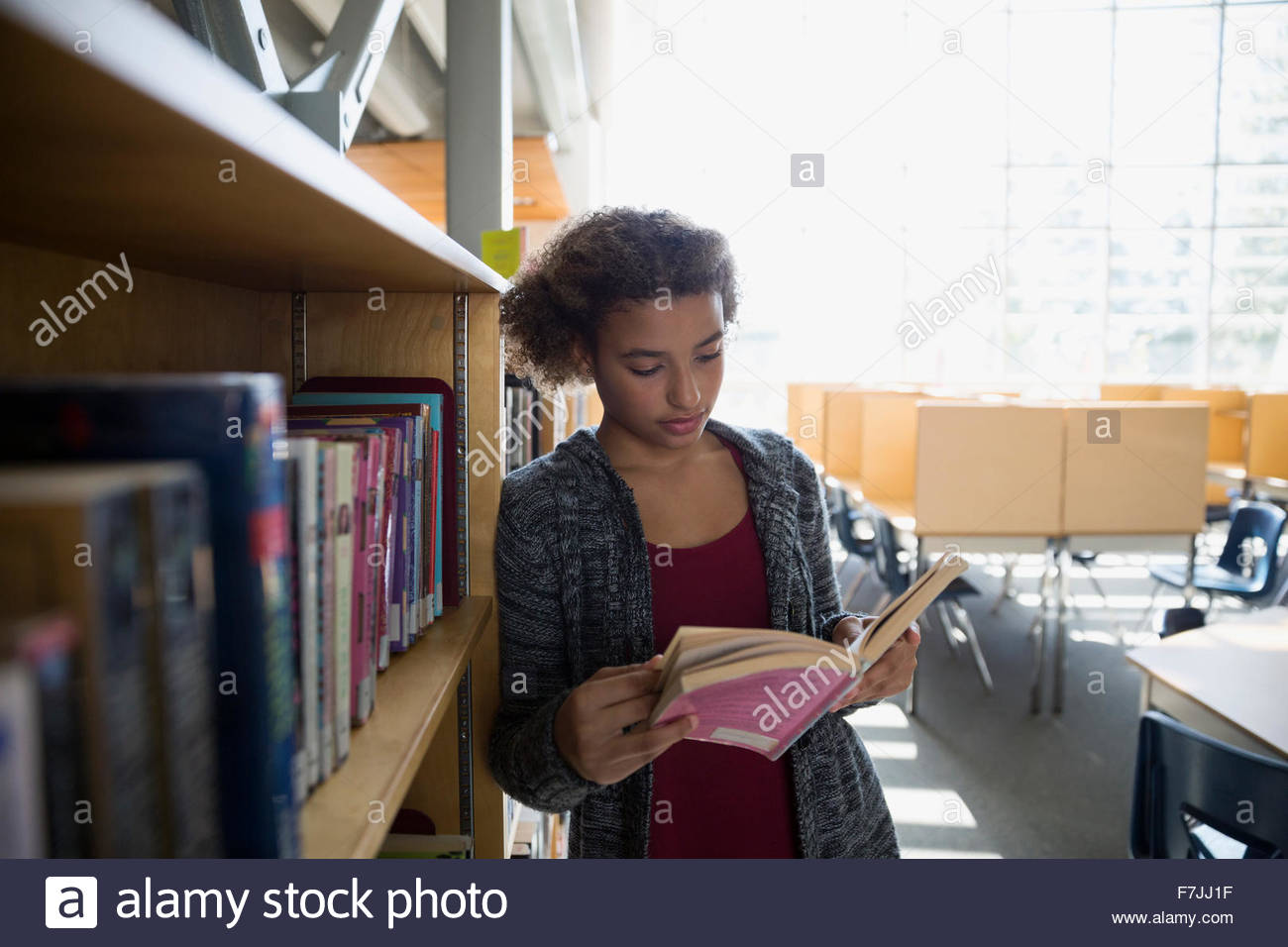 High school student reading book in library Stock Photo - Alamy