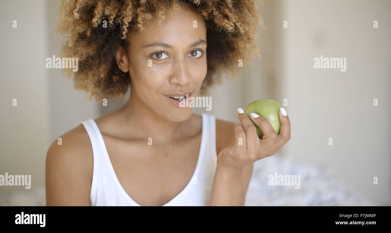 Woman Sitting On Bed And Eating Apple Stock Photo - Alamy