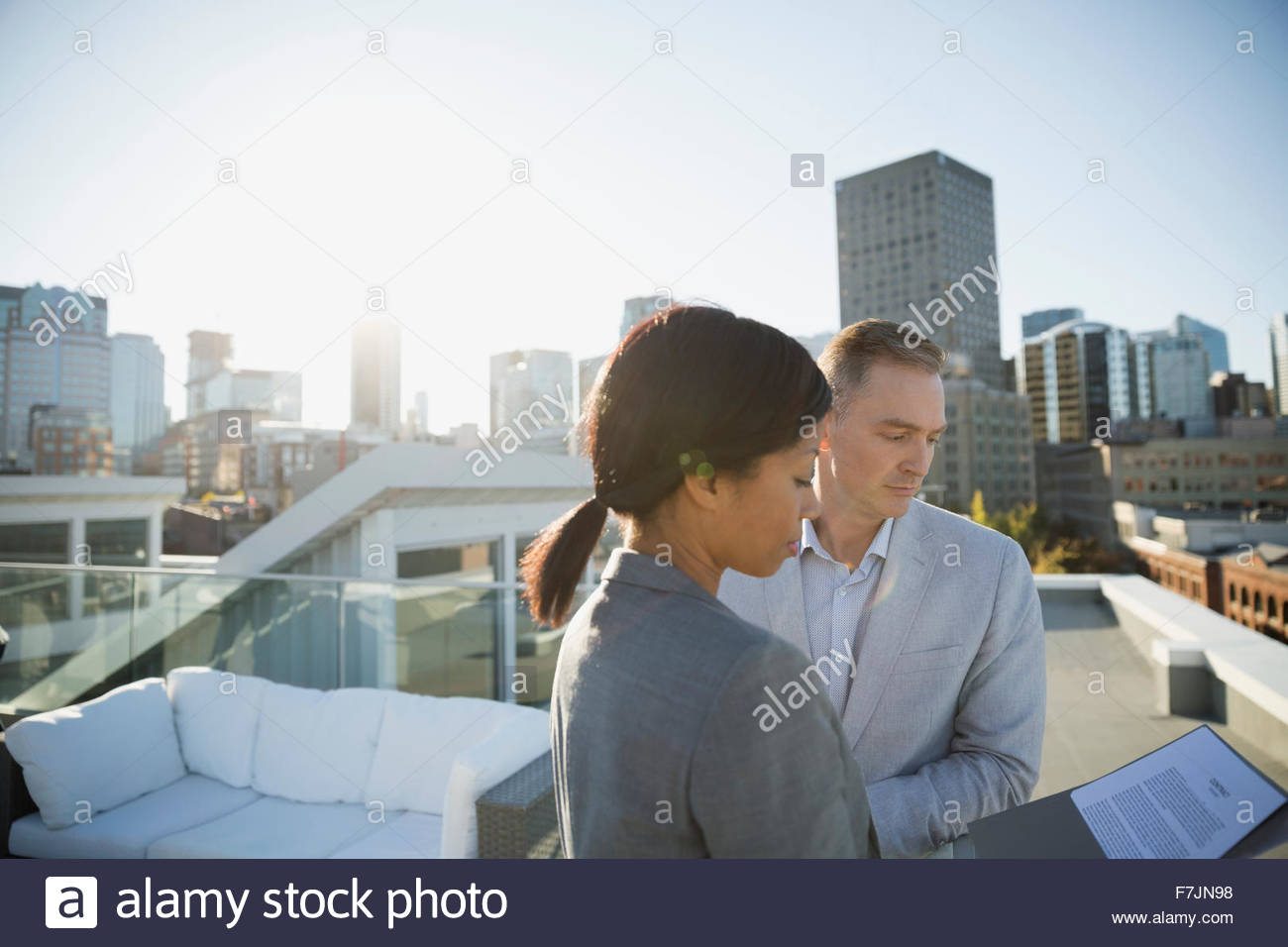 Business people reviewing paperwork on sunny urban rooftop Stock Photo ...