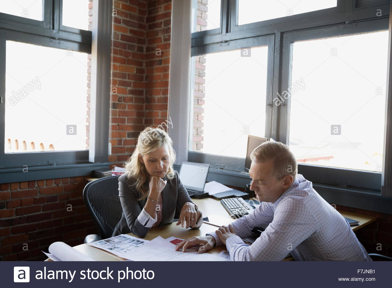 Business people reviewing paperwork at office desk Stock Photo - Alamy