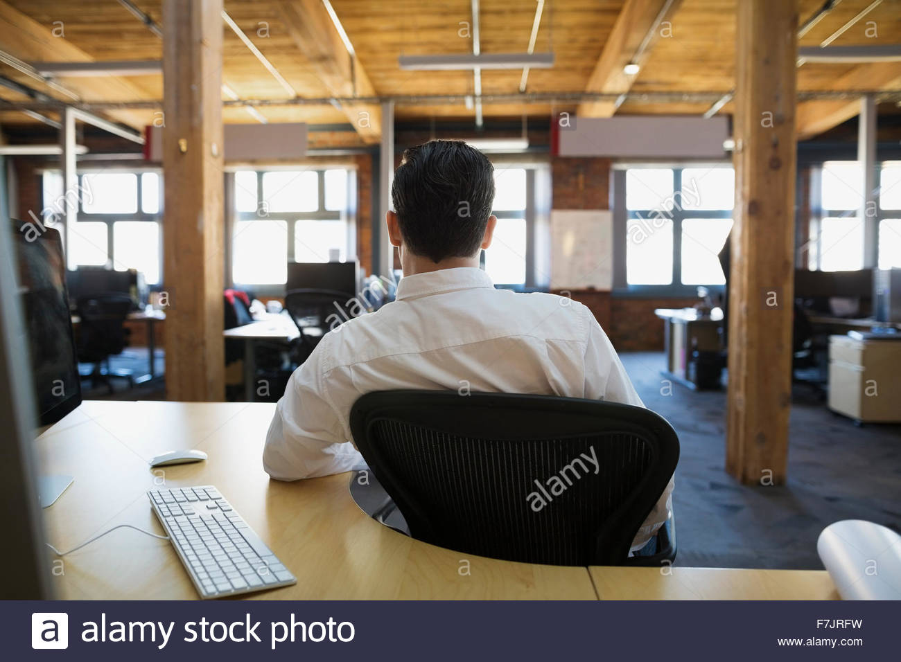 Rear view of businessman looking away open office Stock Photo - Alamy