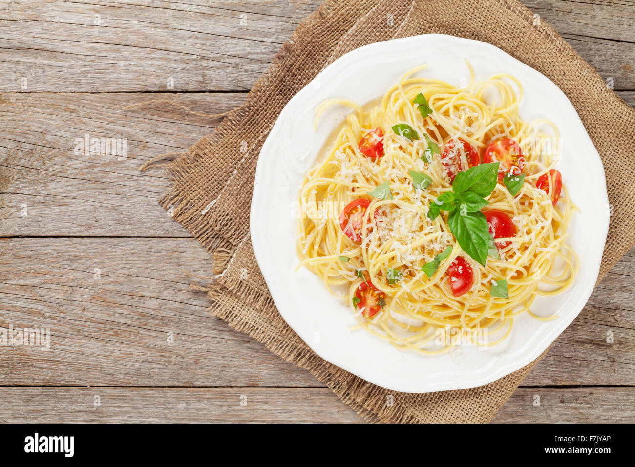 Spaghetti pasta with tomatoes and basil on wooden table. Top view with ...