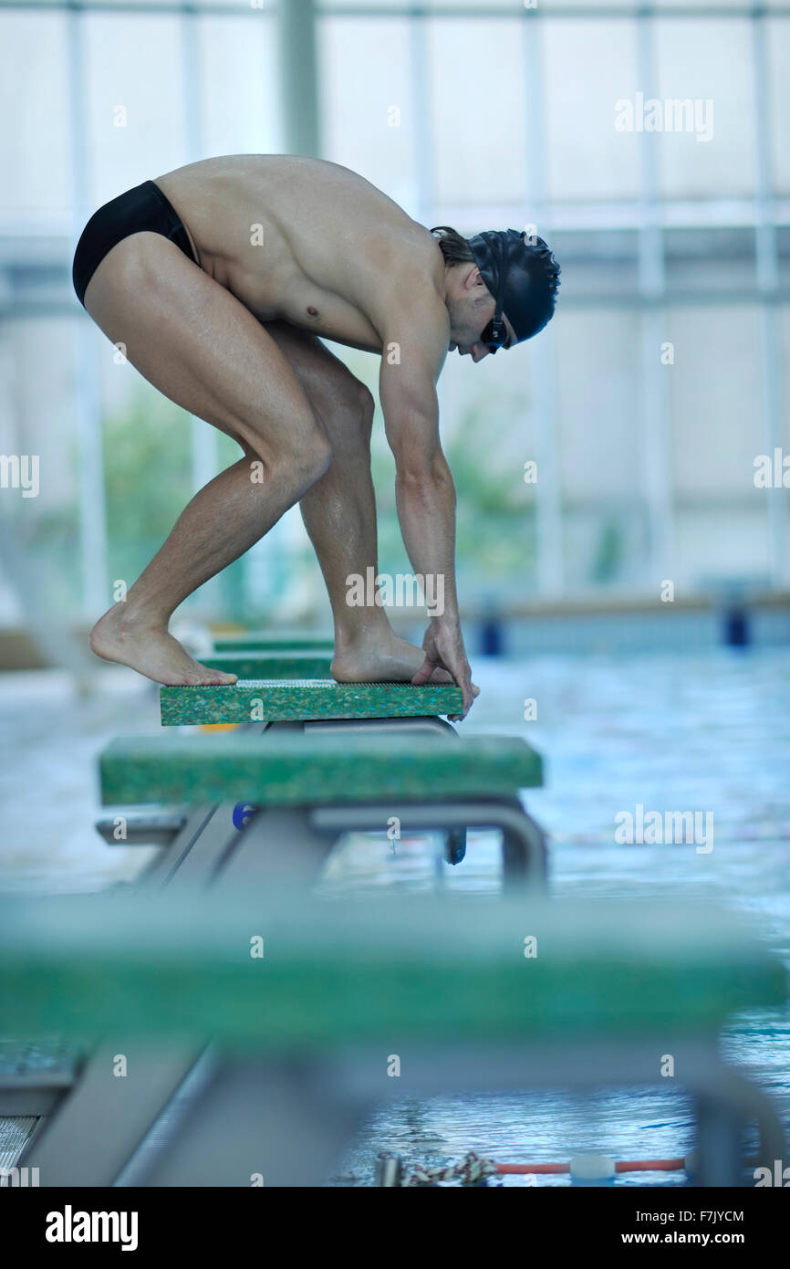 young swimmer on swim start at swimming pool ready for jump race and ...