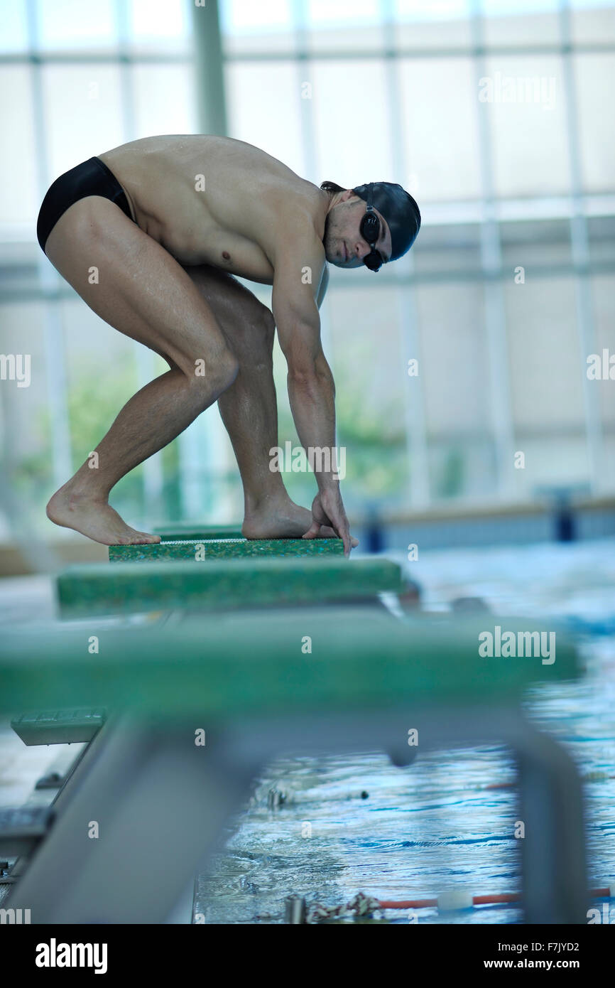 young swimmer on swim start at swimming pool ready for jump race and ...