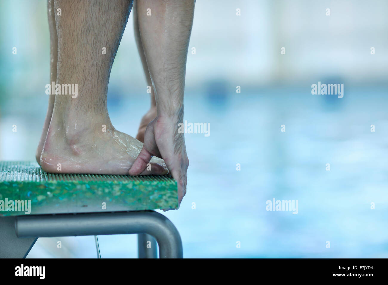 young swimmer on swim start at swimming pool ready for jump race and ...