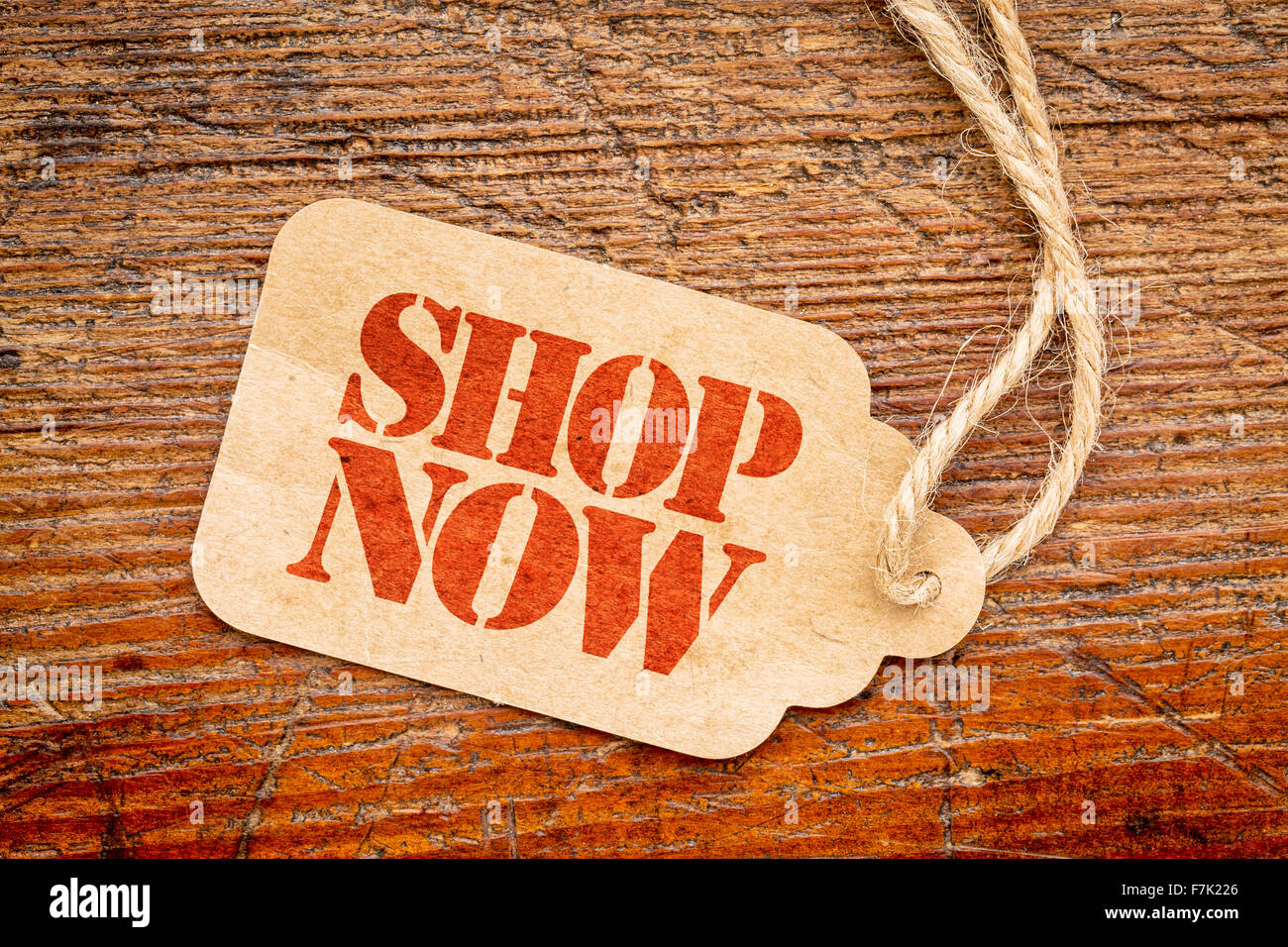 shop now sign - red stencil text on a paper price tag against rustic ...