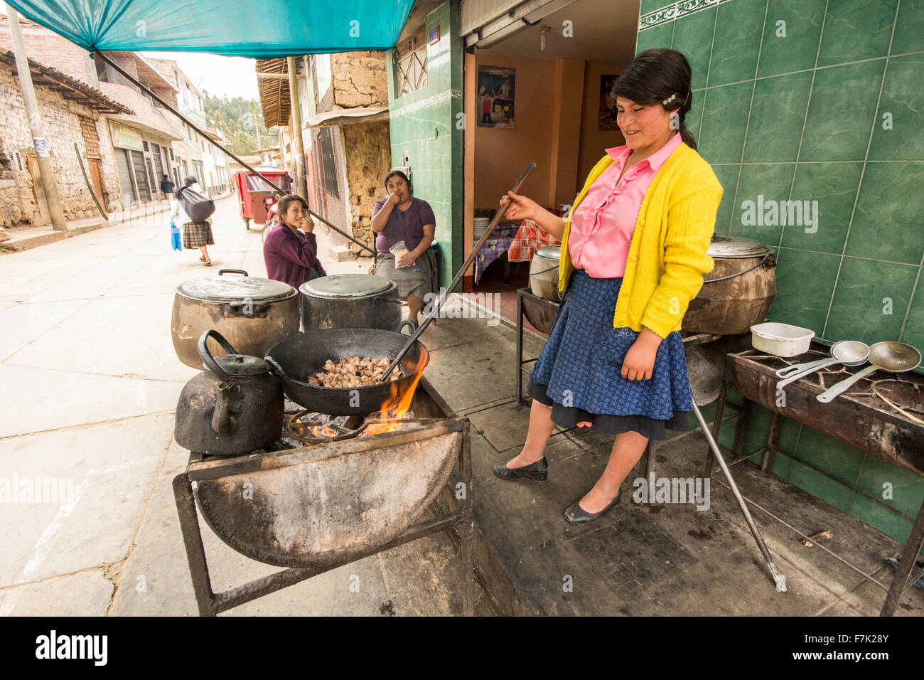 Traditional young Peruvian woman cooks chicharron (deep fried pork) at ...