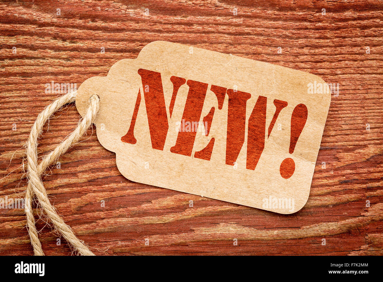 New sign - red stencil text on a paper price tag against grunge wood ...