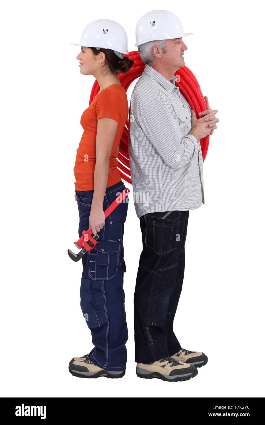 Experienced plumber stood back to back with young helper Stock Photo ...