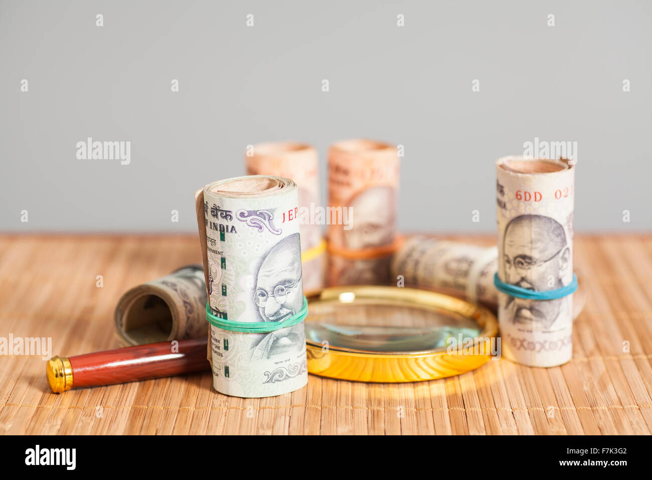 Rolls of Indian Currency Rupee Notes with magnifying glass on wooden ...